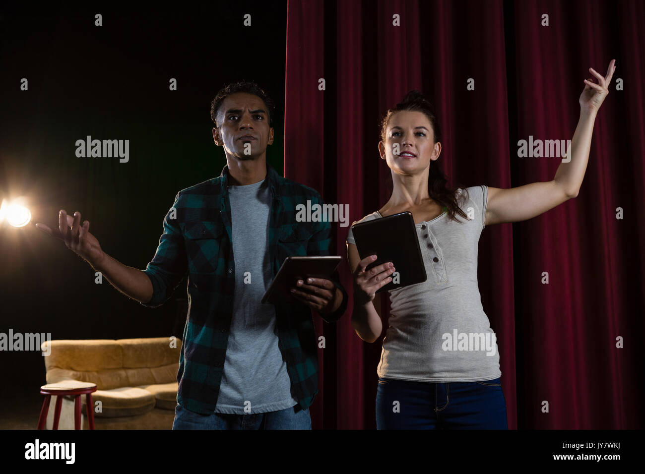 Actors rehearsing on stage while using digital tablet in theatre Stock ...