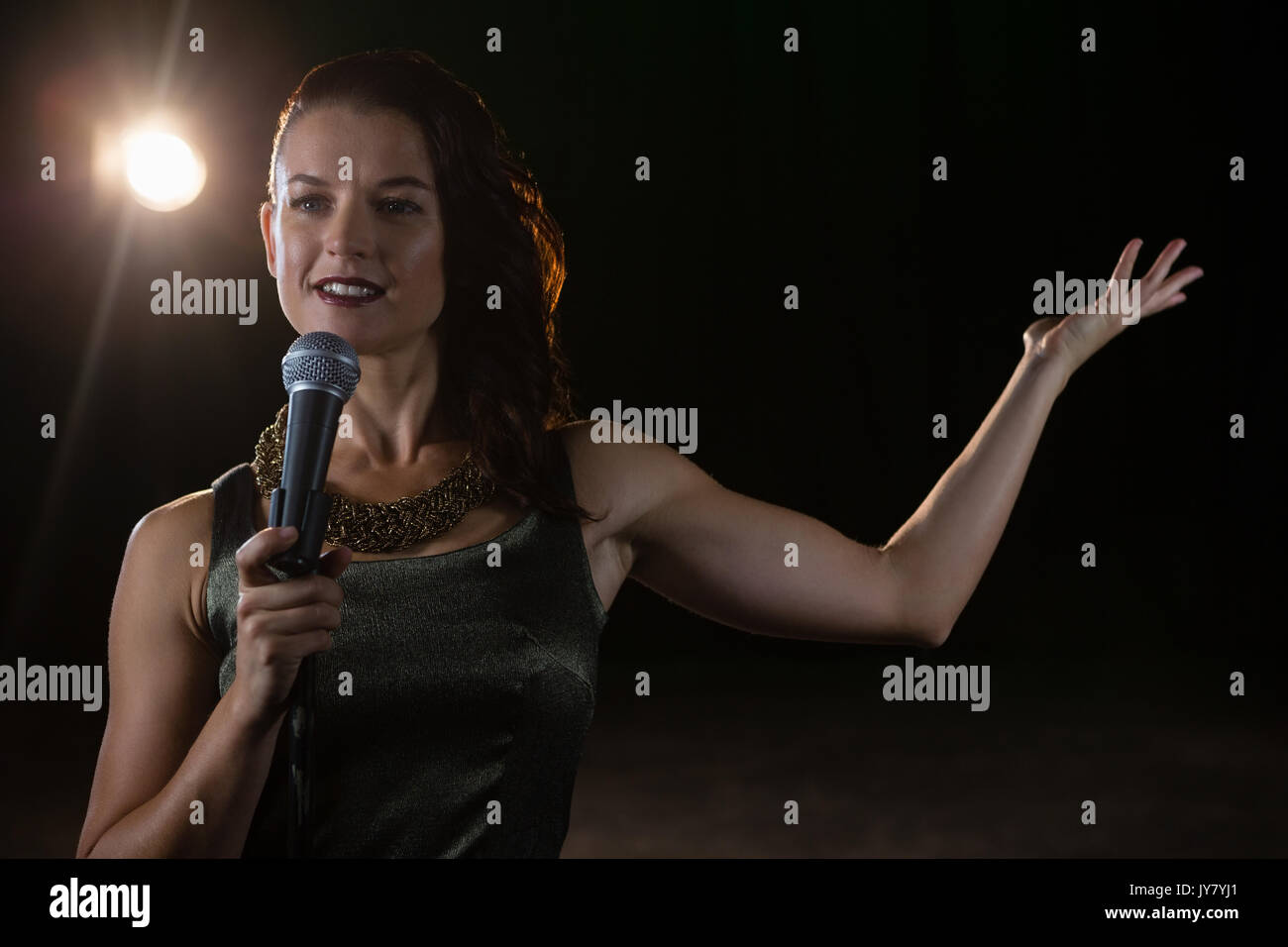 Female singer singing into a microphone in stage Stock Photo - Alamy