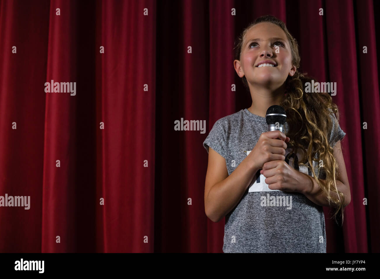 Smiling girl holding microphone on stage in theatre Stock Photo - Alamy