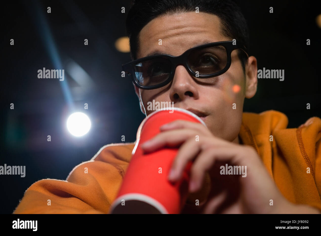 Man drinking cold drinks while watching movie in theatre Stock Photo ...