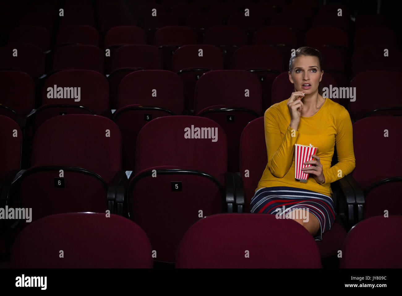 Concentrated woman eating popcorn watching hi-res stock photography and ...