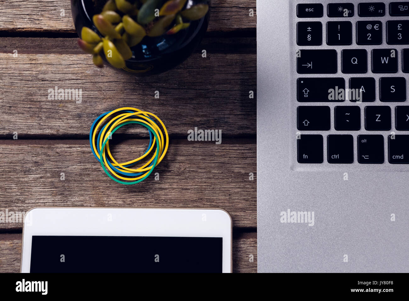 Close-up of digital tablet, laptop, wire and pencil holder on wooden ...