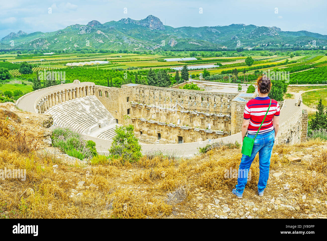 The young female tourist watches the ancient Aspendos amphitheater and ...