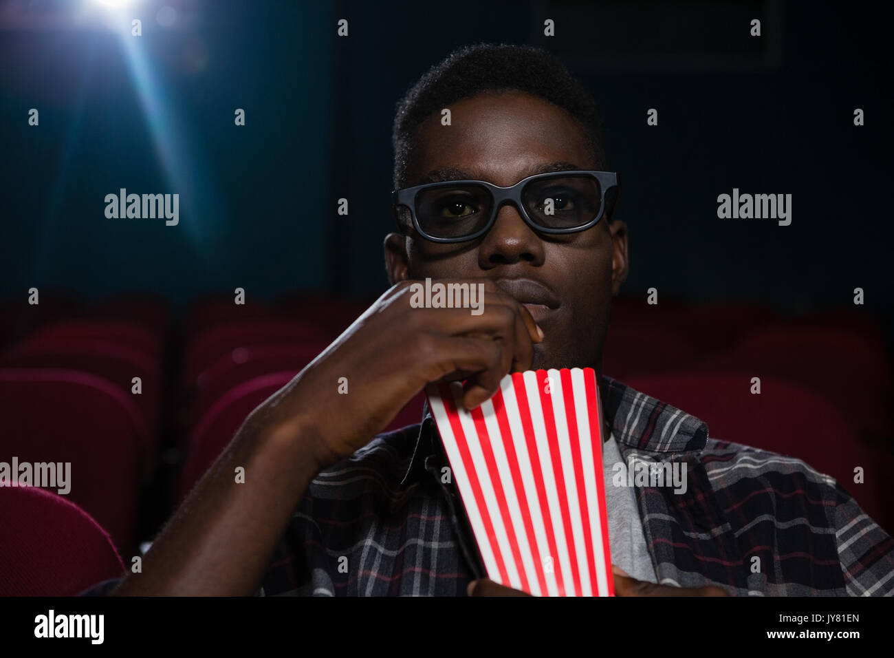 Man having popcorn while watching movie in theatre Stock Photo - Alamy