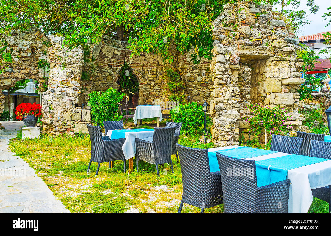 The tables and chairs on the lawn next to the ruins of ancient building ...
