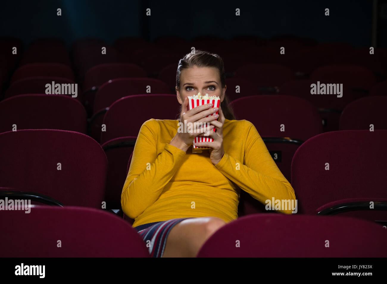 Woman scared while watching movie in theatre Stock Photo - Alamy