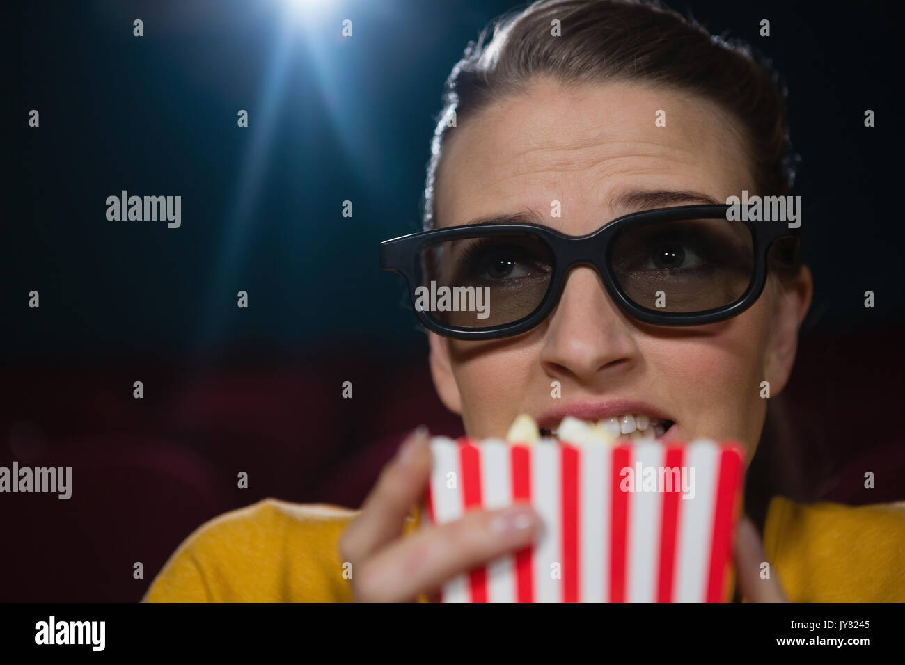 Woman scared while watching movie in theatre Stock Photo - Alamy