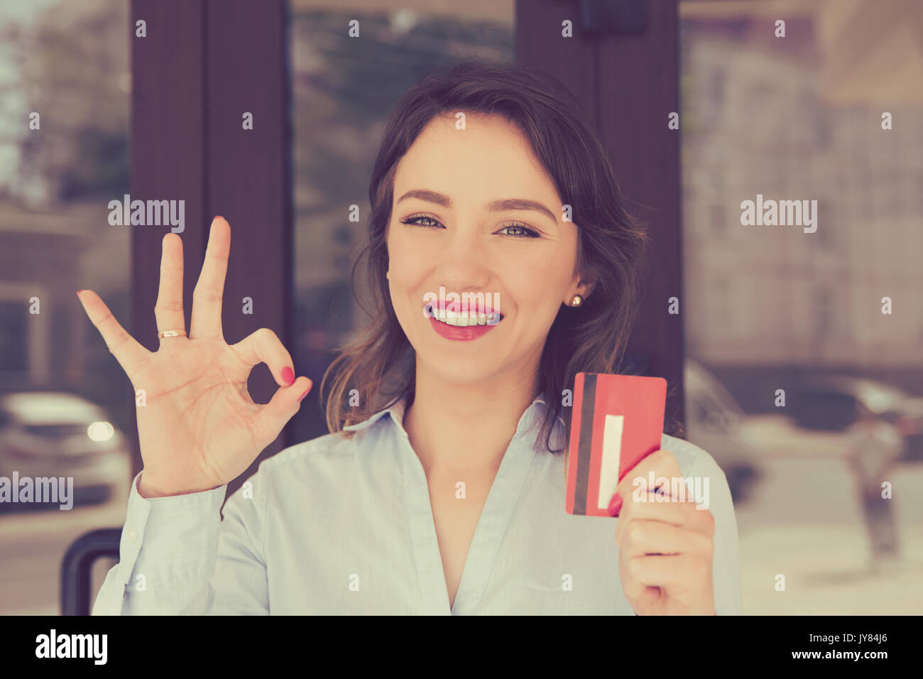 Toothy smile woman holding showing credit card near office store ... Toothy smile woman holding showing credit card near office store ...