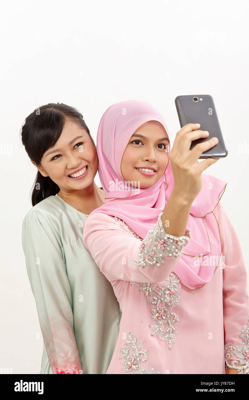 two happy young muslim woman take self portrait with handphone Stock ...