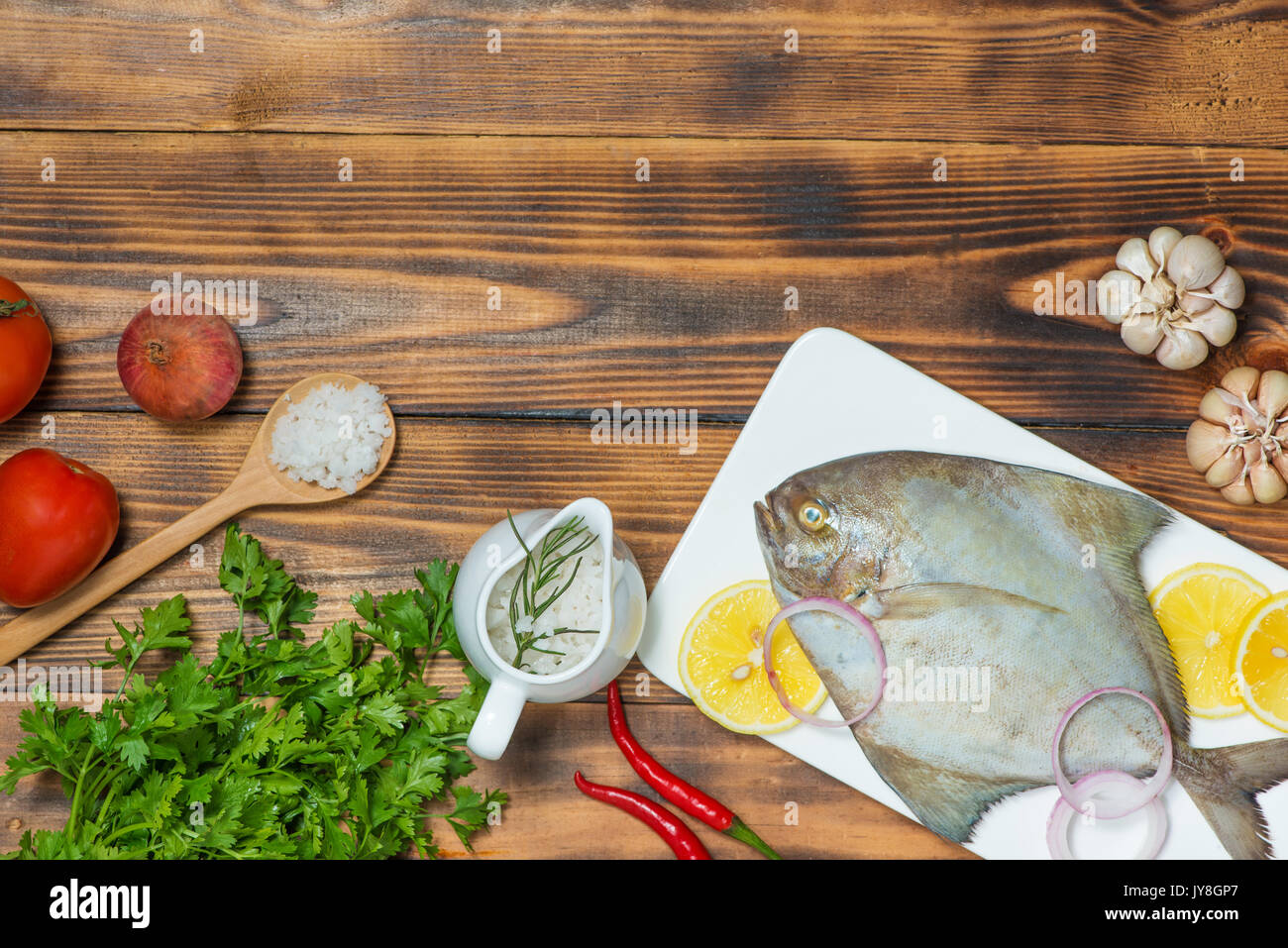 Fish dish cooking with various ingredients. Fresh raw fish decorated ...