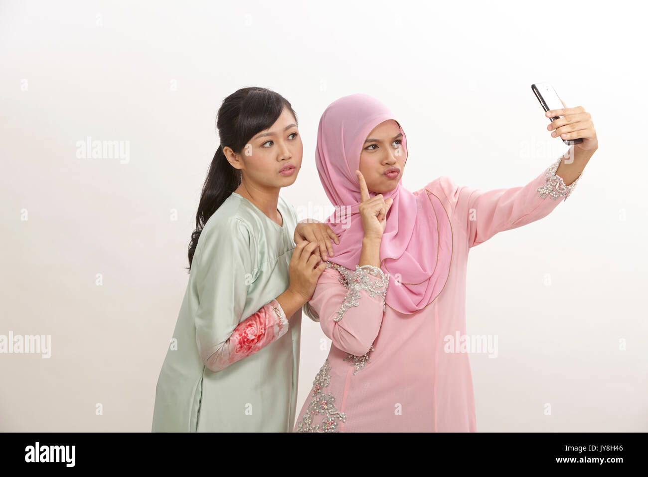 two happy young muslim woman take self portrait with handphone Stock ...