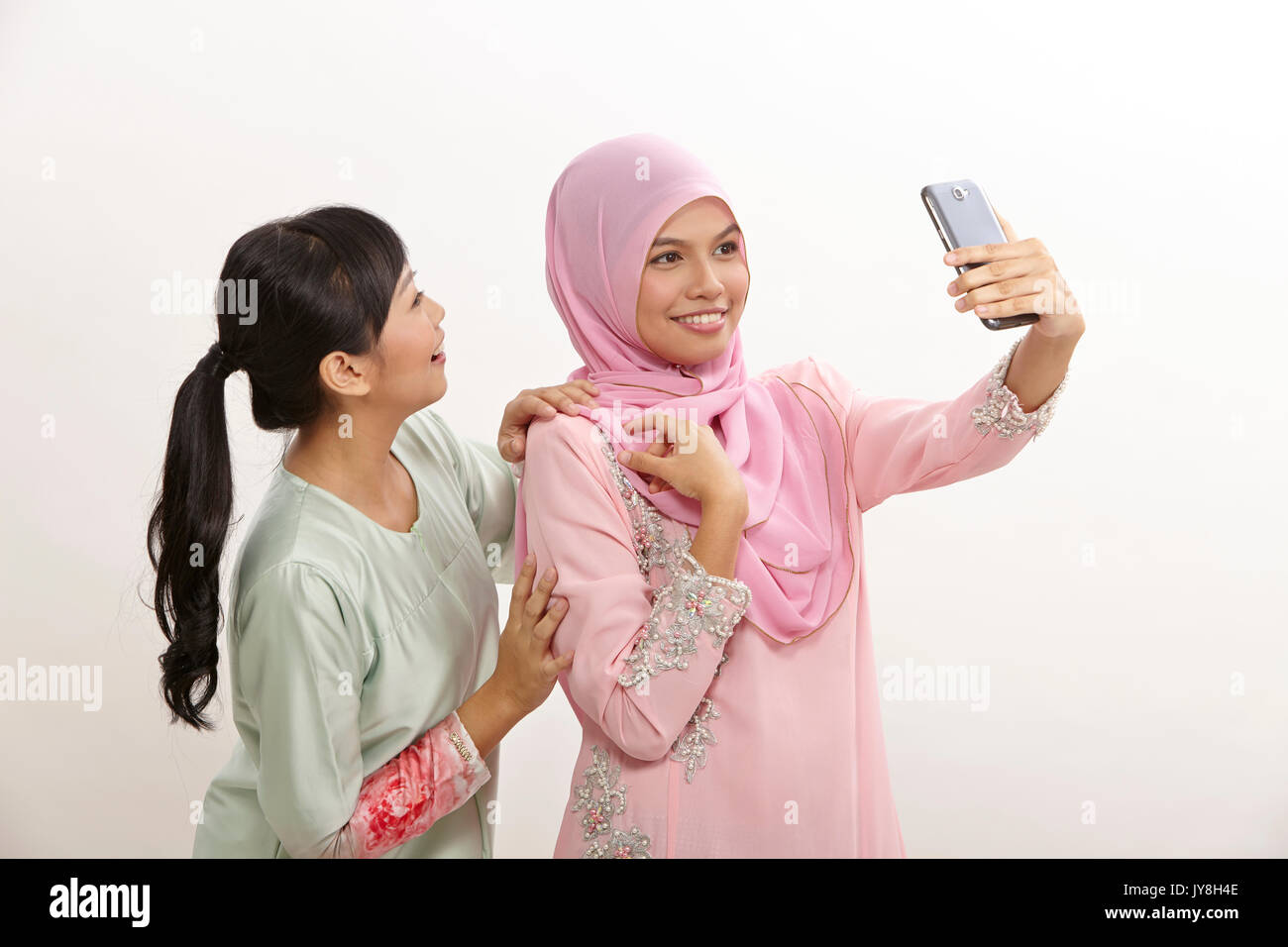 two happy young muslim woman take self portrait with handphone Stock ...