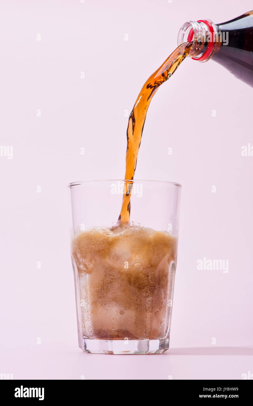 Pouring cola from bottle into glass with splashing Stock Photo - Alamy