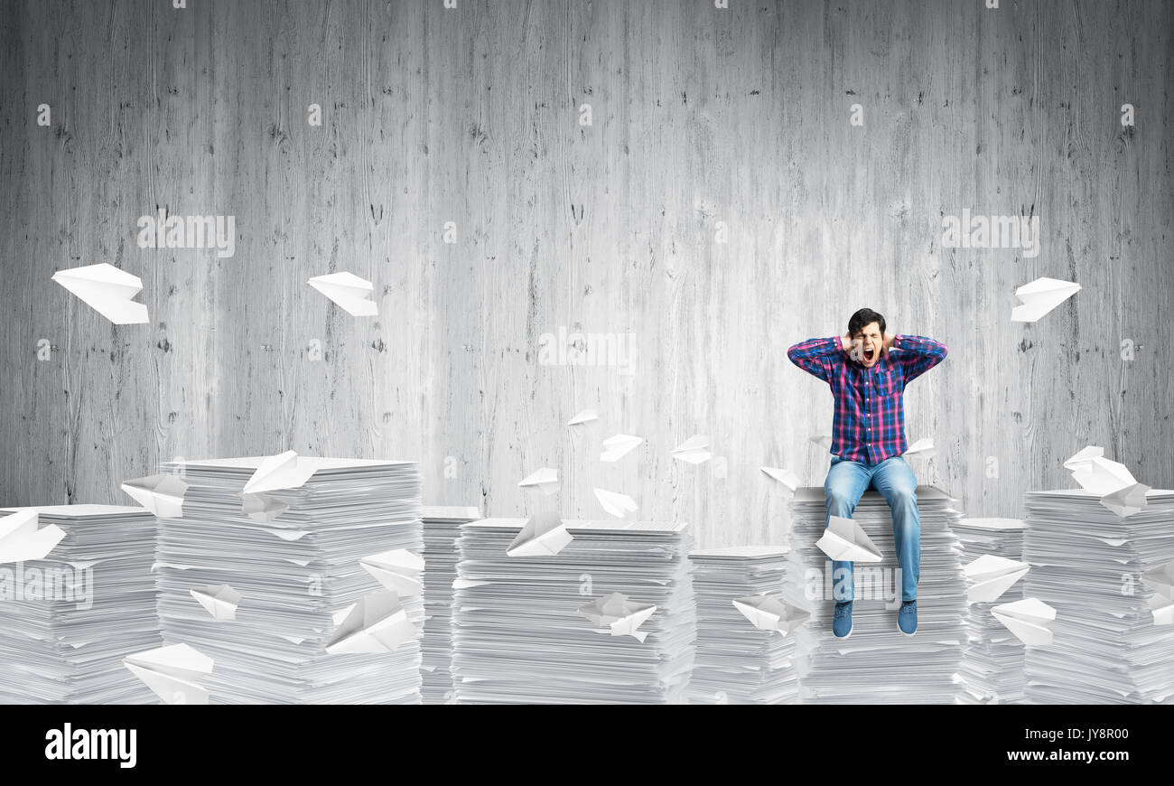 Attractive man sitting on pile of paper documents Stock Photo - Alamy