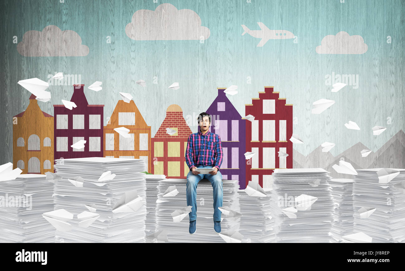 Young man sitting on pile of paper documents Stock Photo - Alamy
