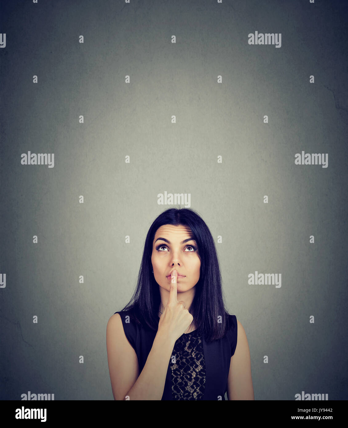 Serious young woman looking up thinking Stock Photo - Alamy