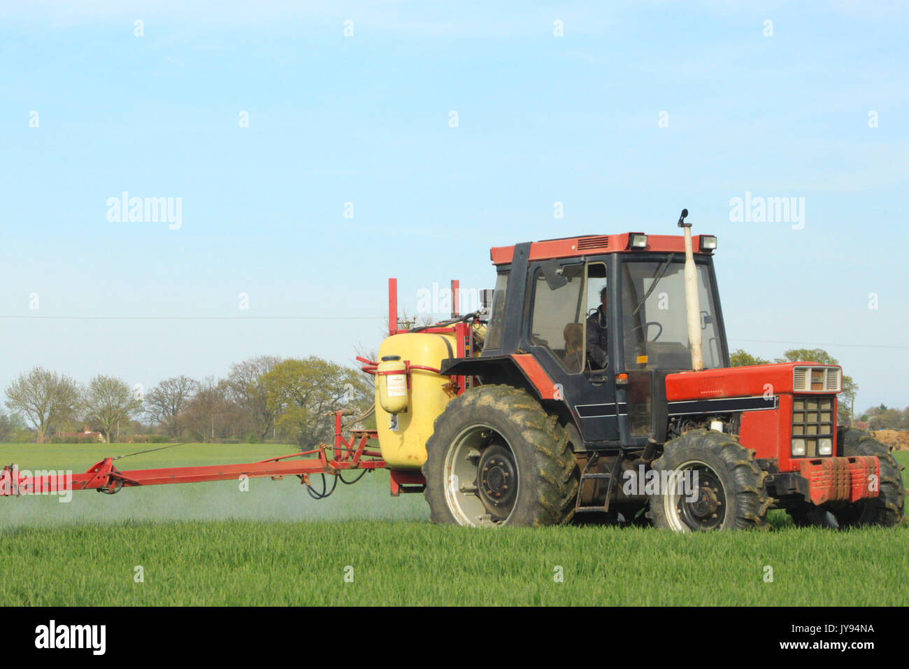 Tractor spraying pesticides on grass. Tractor spraying wheat field with ...