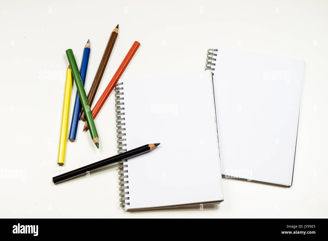 Sketchbook and crayons on a white table. White table and white ...