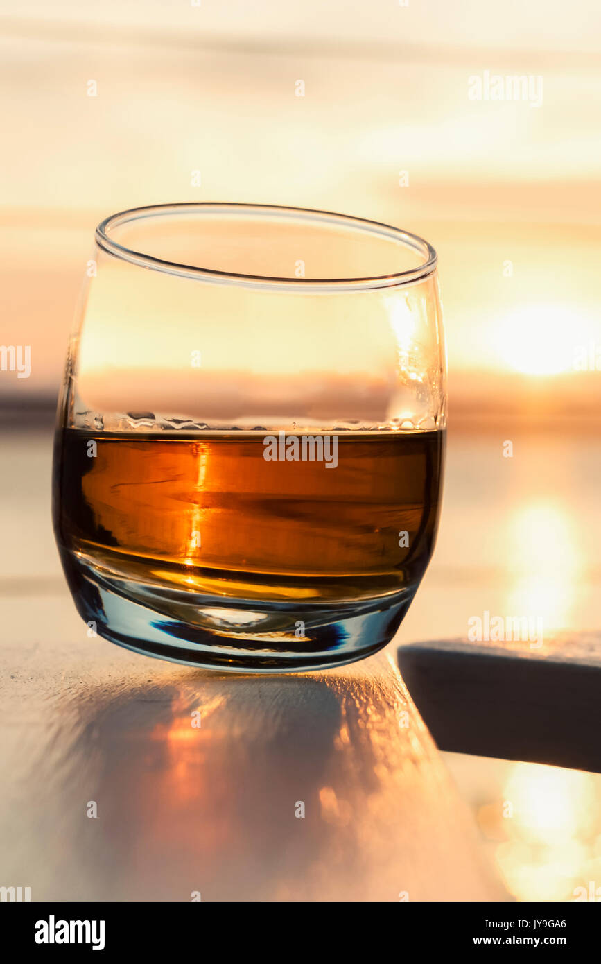 A single dram of fine scotch whiskey on arm of chair overlooking a ...