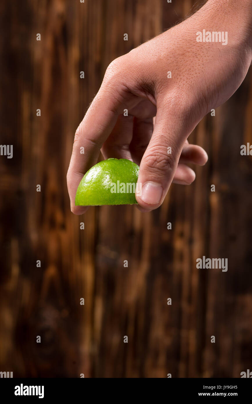Hand squeeze lime with lime drop on dark wooden background Stock Photo ...