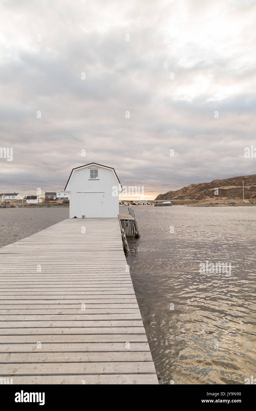White boathouse on long dock on a cloudy day at sunset near Twillingate ...