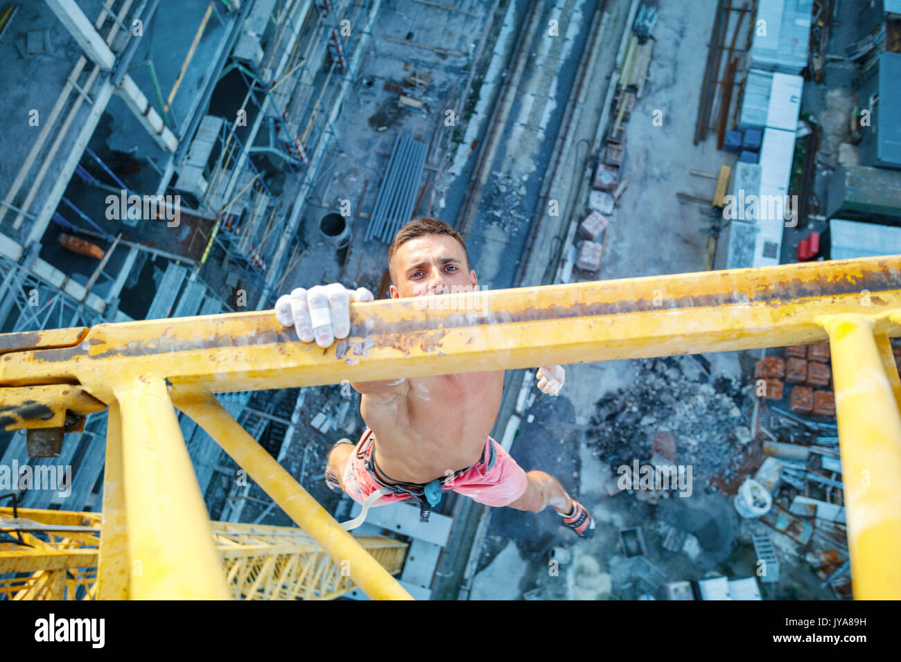 Urban climbing: rock climber hanging on jib of construction crane with ...