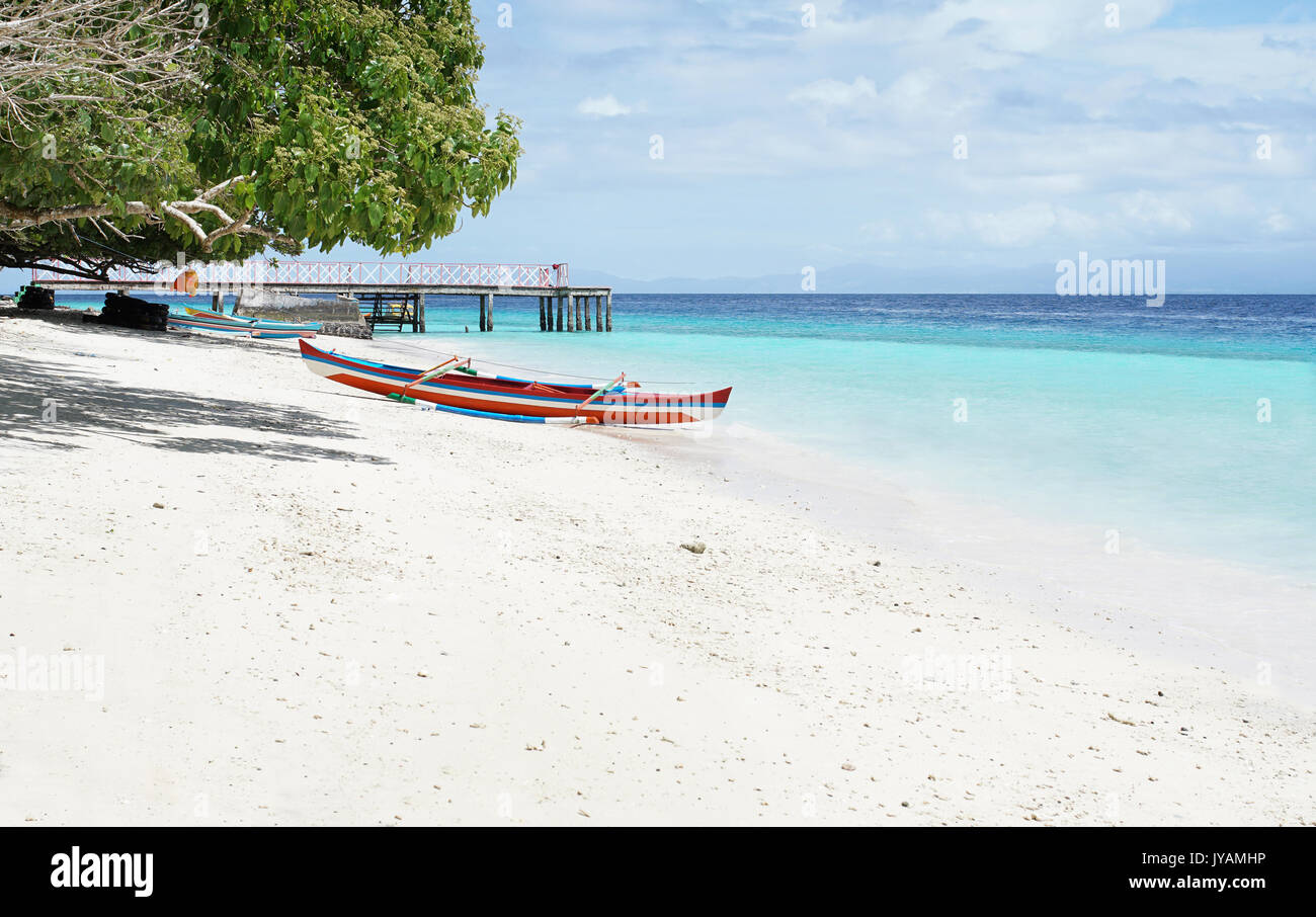 Red white blue colored small empty canoe boat stranded on a tropical ...