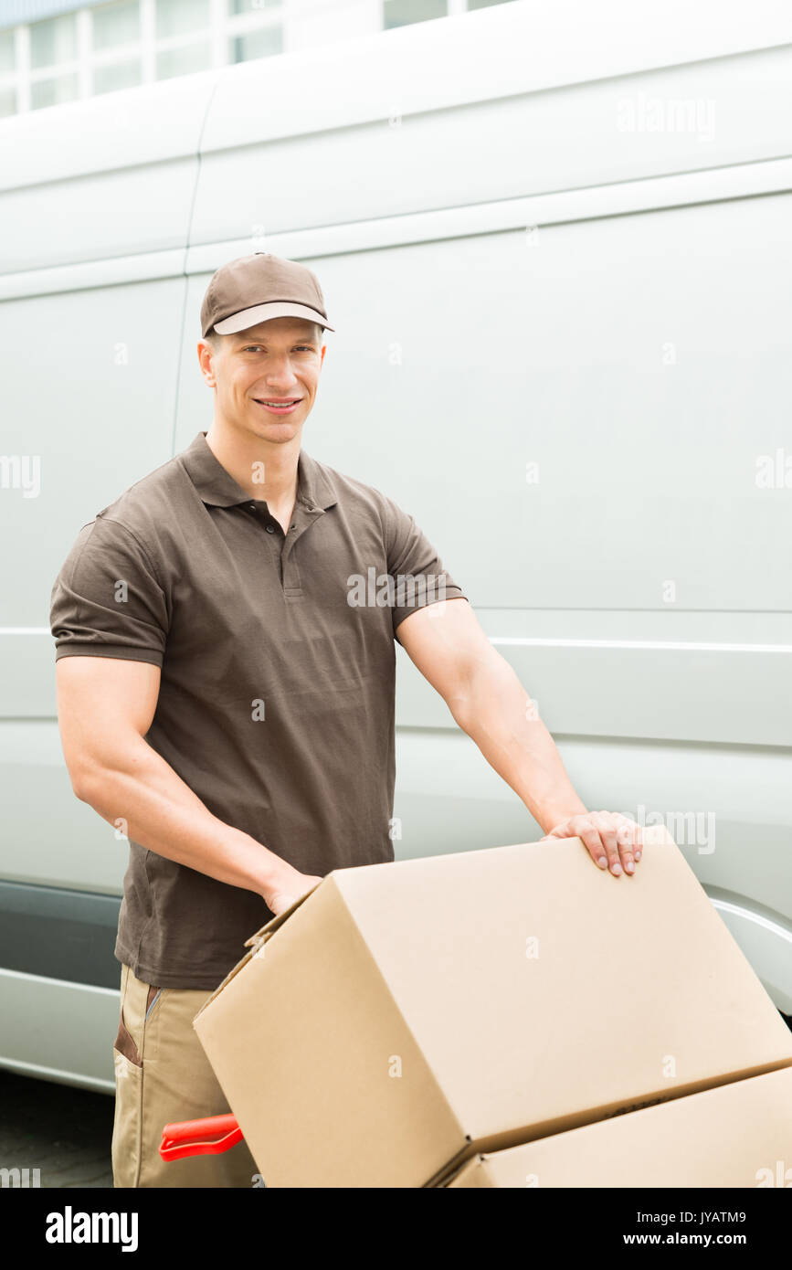 Young Delivery Man Holding Trolley With Cardboard Boxes Stock Photo - Alamy