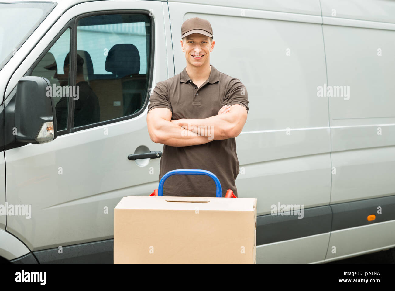 Young Happy Delivery Man With Cardboard Boxes On Trolley In Front Of ...