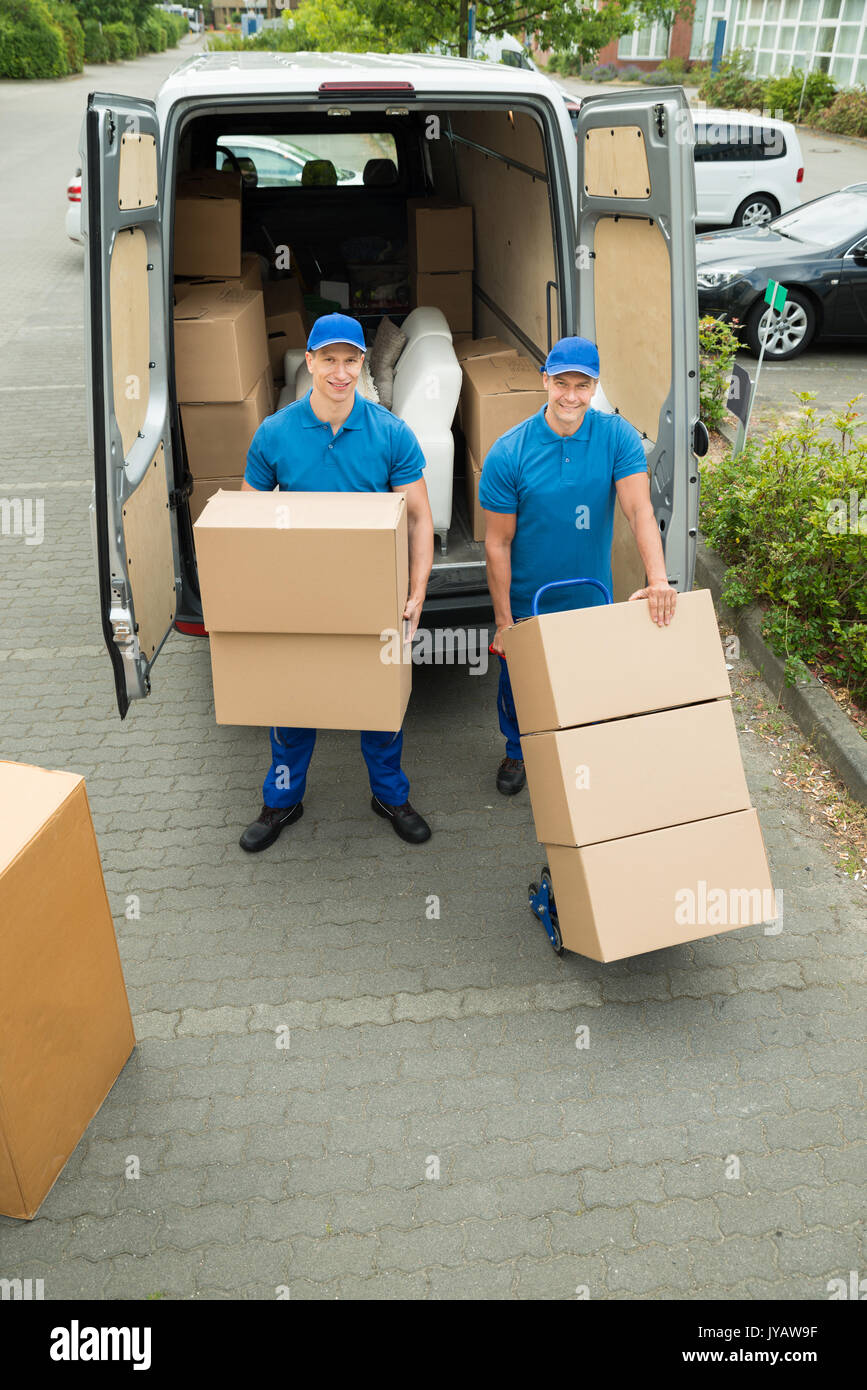 Two Happy Male Workers Loading Stack Of Cardboard Boxes In Truck Stock ...