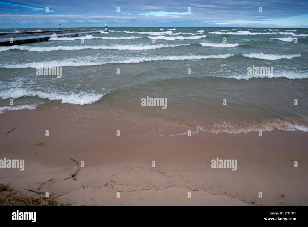 Waves crashing into the piers of the White Lake Channel and the beach ...