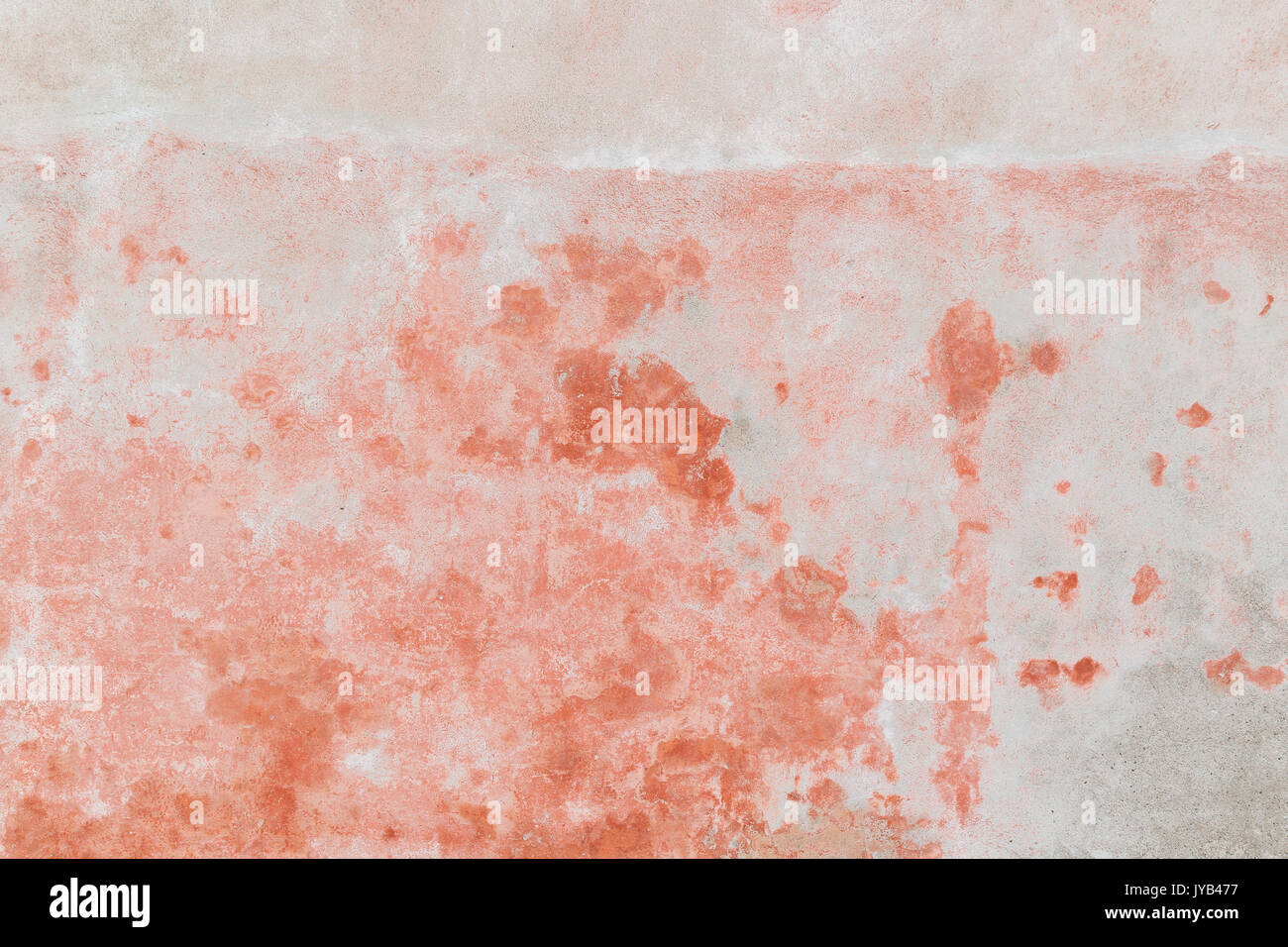 Weathered and aged concrete wall, bleached red paint peeled off ...