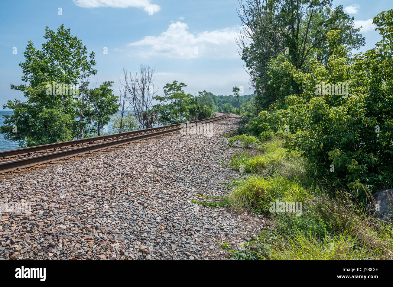 Railroad tracks on the edge of Lake Champlain with trees and crushed ...