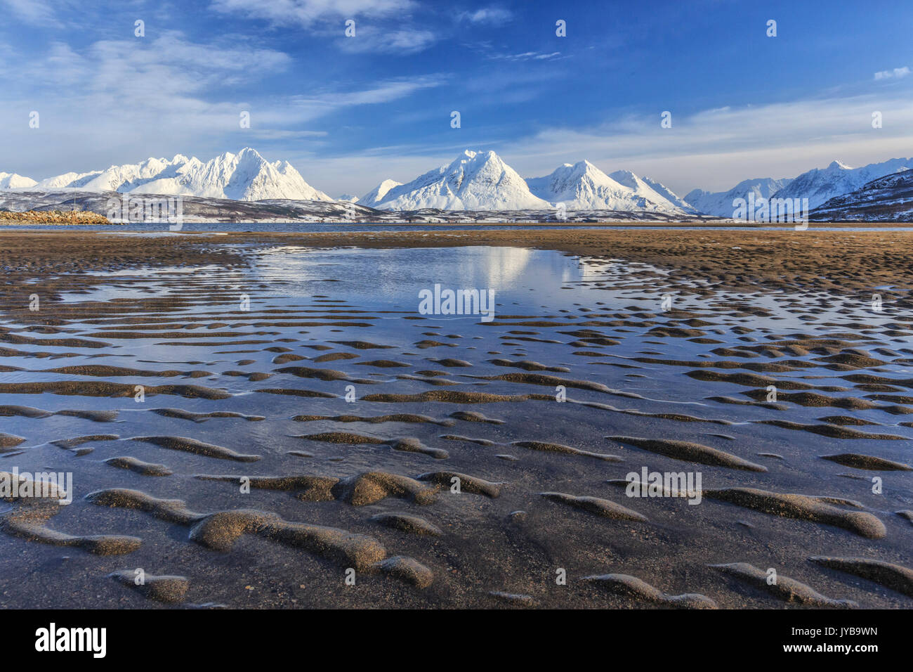 The icy sandy beach surrounding the snow capped mountains Breivikeidet ...