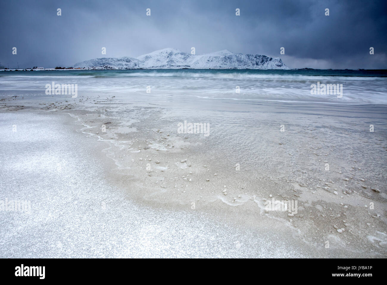 Waves of the icy sea on the beach in the background the snowy peaks ...
