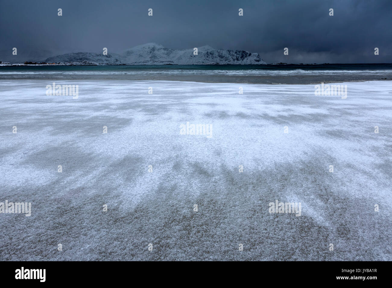 Waves of the icy sea on the beach in the background the snowy peaks ...