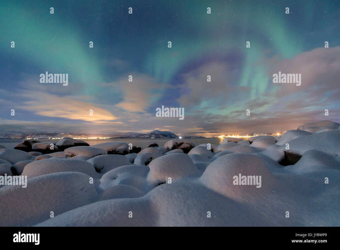 The pink light and the aurora borealis illuminate the snowy landscape ...