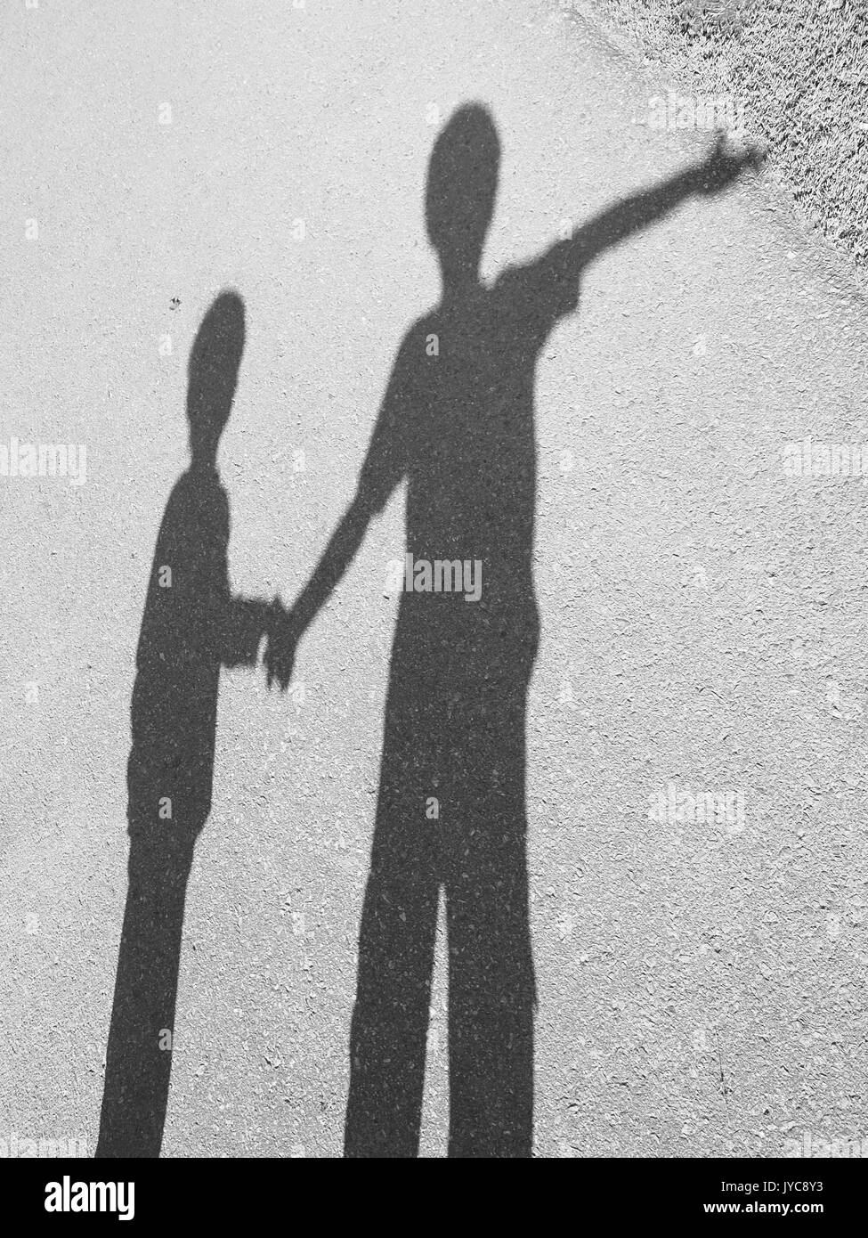 Shadows cast on the sidewalk by two children holding hands, one ...