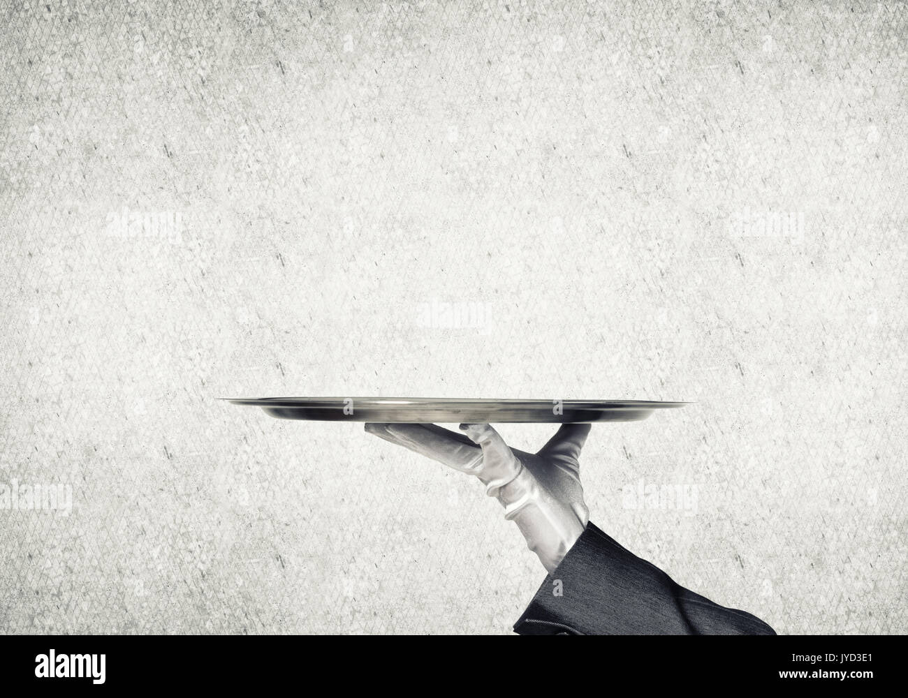 Hand of butler holding empty metal tray against concrete background ...