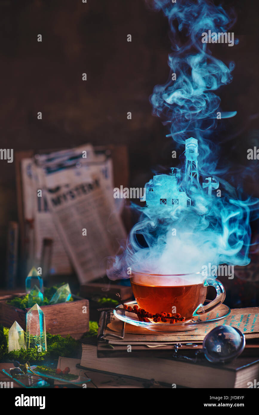 Witch kitchen. Steaming glass cup of tea with herbs and berries in a ...