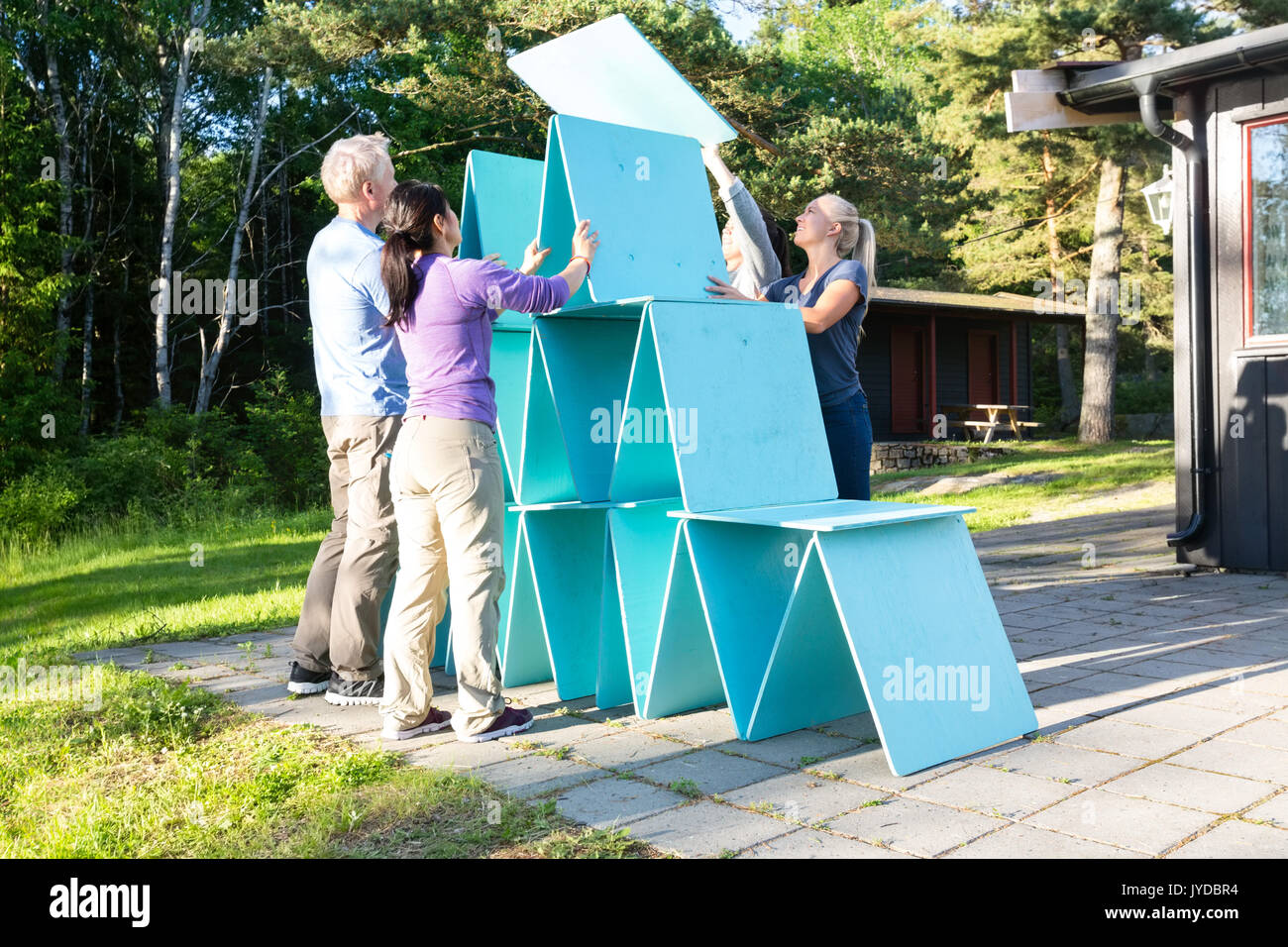 Friends Making Pyramid With Wooden Planks On Patio In Forest Stock ...
