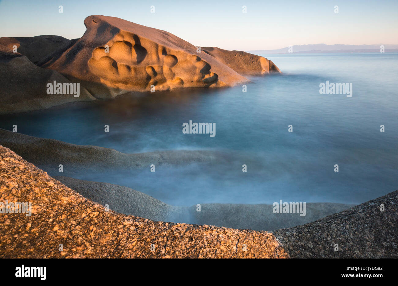 Sunset on modeled cliffs by wind framing blue sea Capo Testa Santa ...