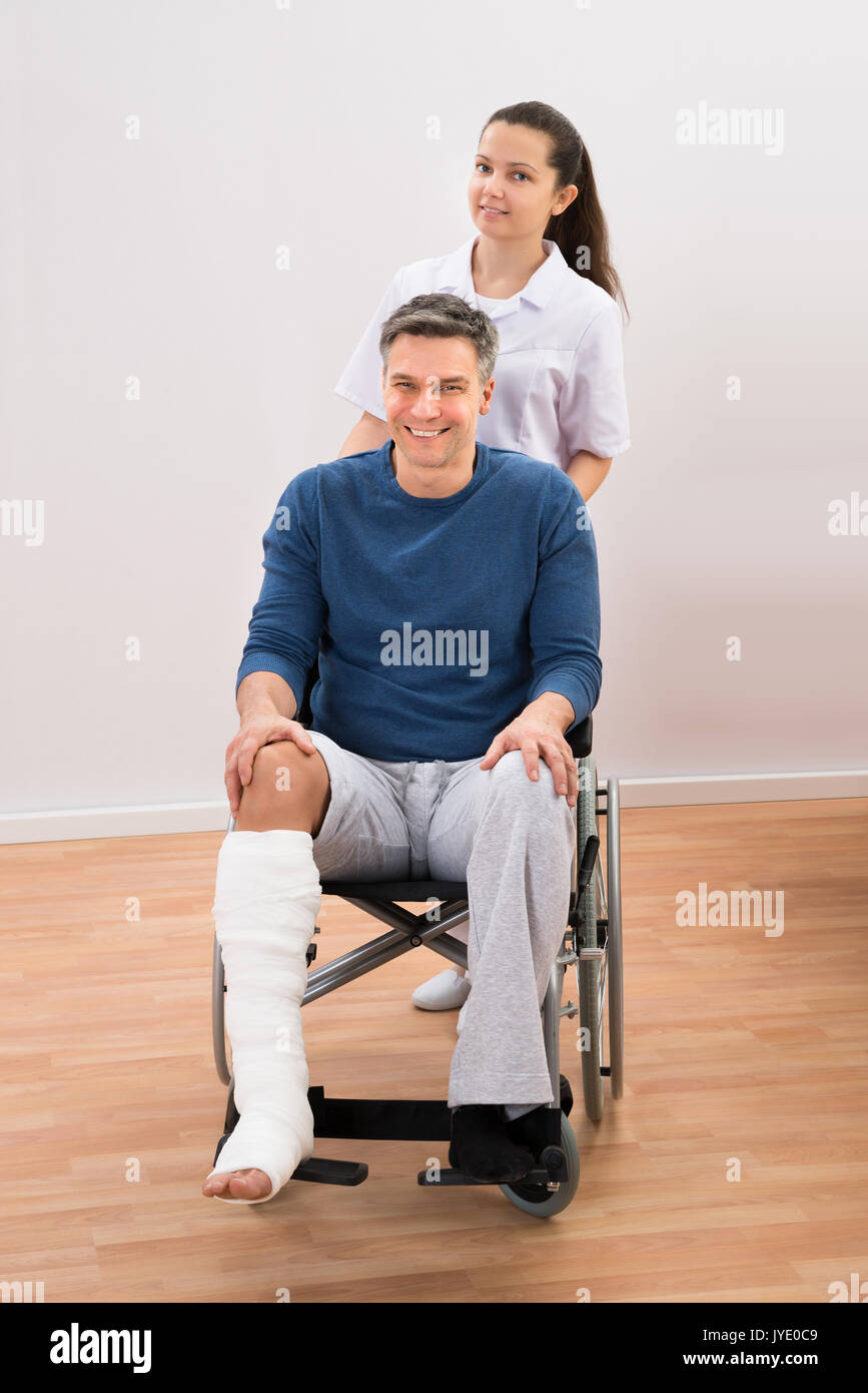 Nurse Assisting Disabled Patient Sitting On Wheelchair Stock Photo - Alamy