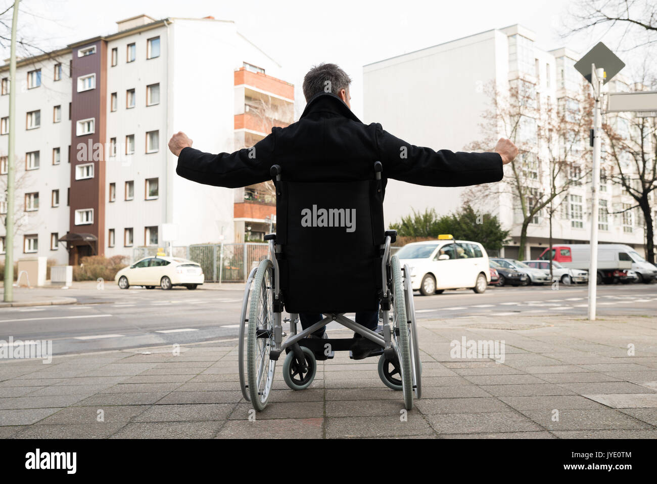 Rear View Of A Disabled Man On Wheelchair With Hand Raised Stock Photo ...
