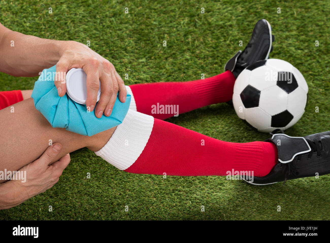 Male athlete holding ice pack to knee hi-res stock photography and ...