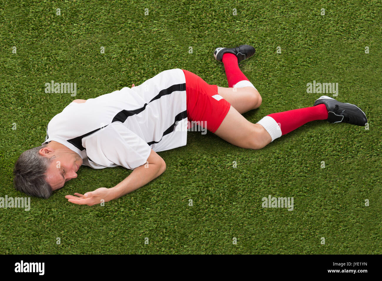 Male Soccer Player Suffering From Injury Lying On Grass Stock Photo - Alamy