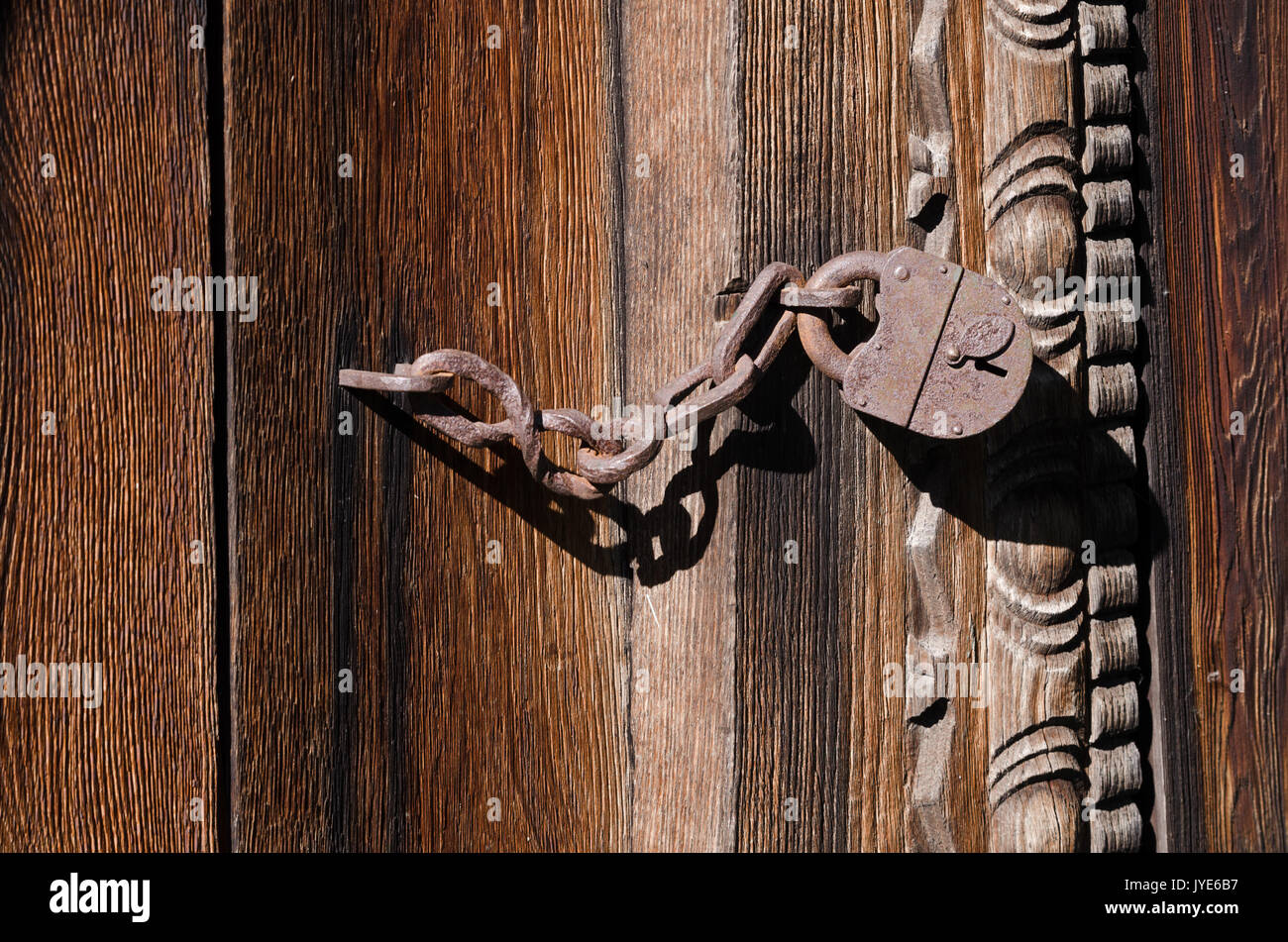 Iron lock on a solid chain hanging on a wooden gate, a texture, a ...