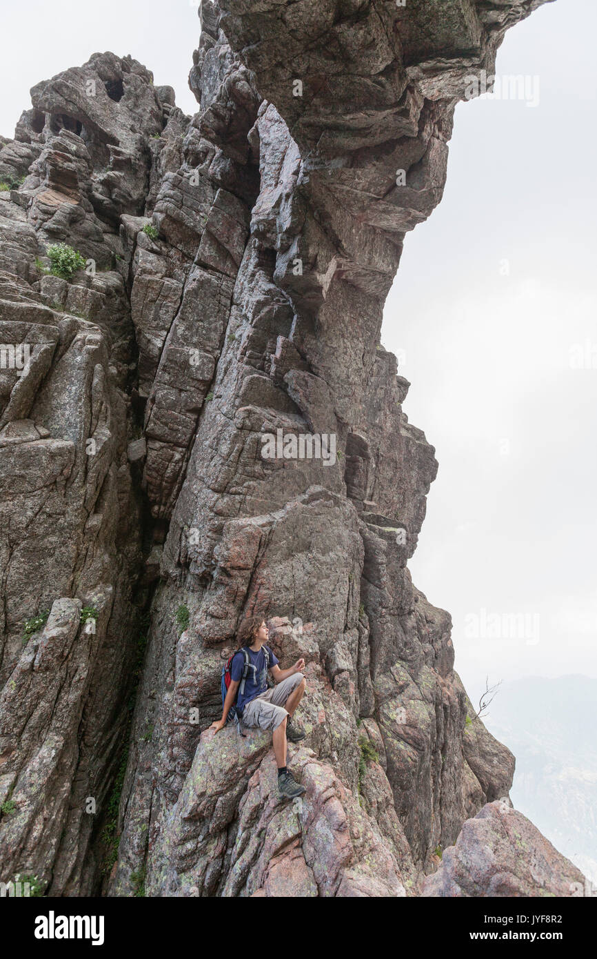 Hiker sits on the rocks of the natural arch Col de Bavella (Pass of ...