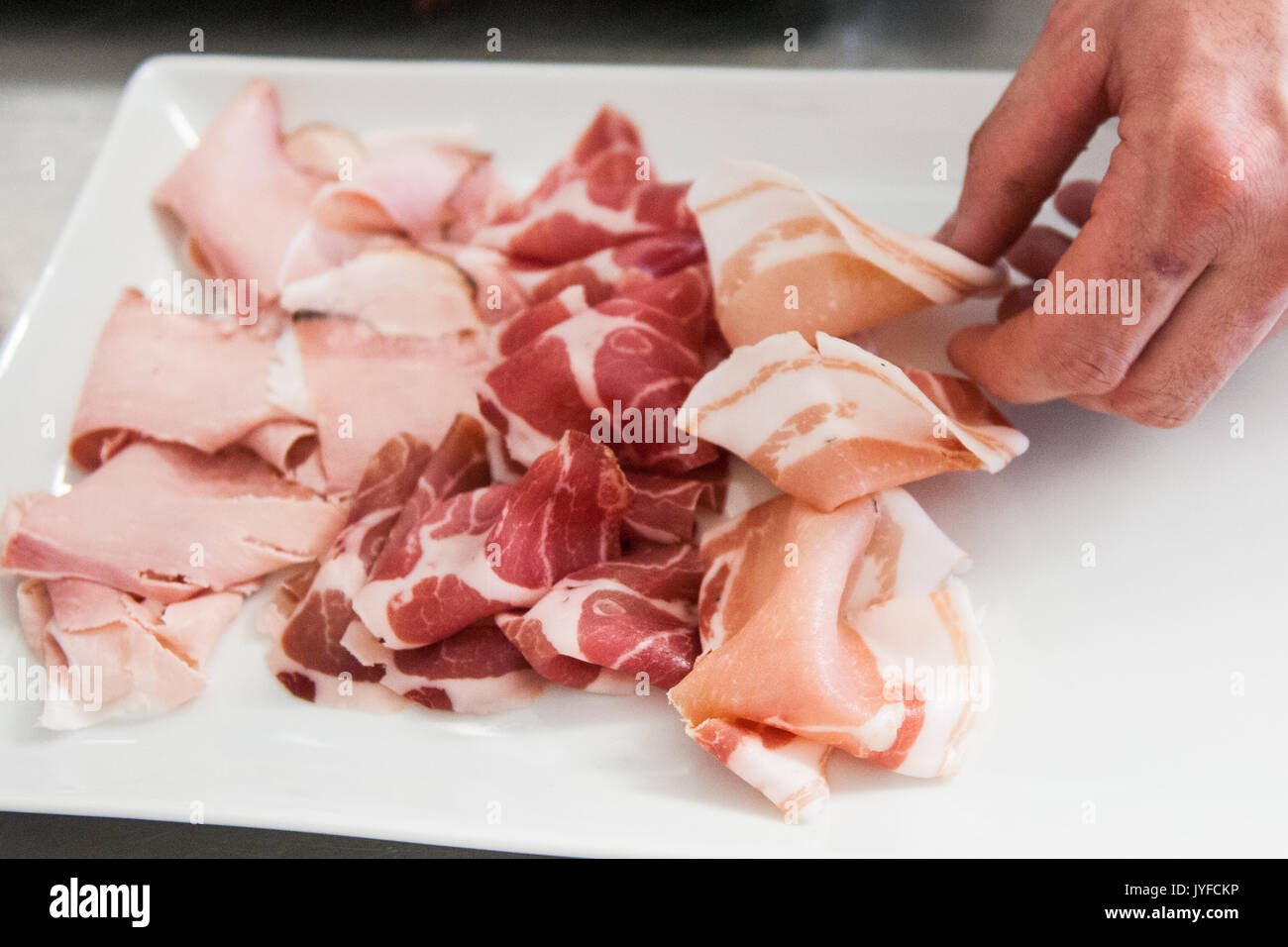 A chef plates cold cuts on a dish Stock Photo - Alamy