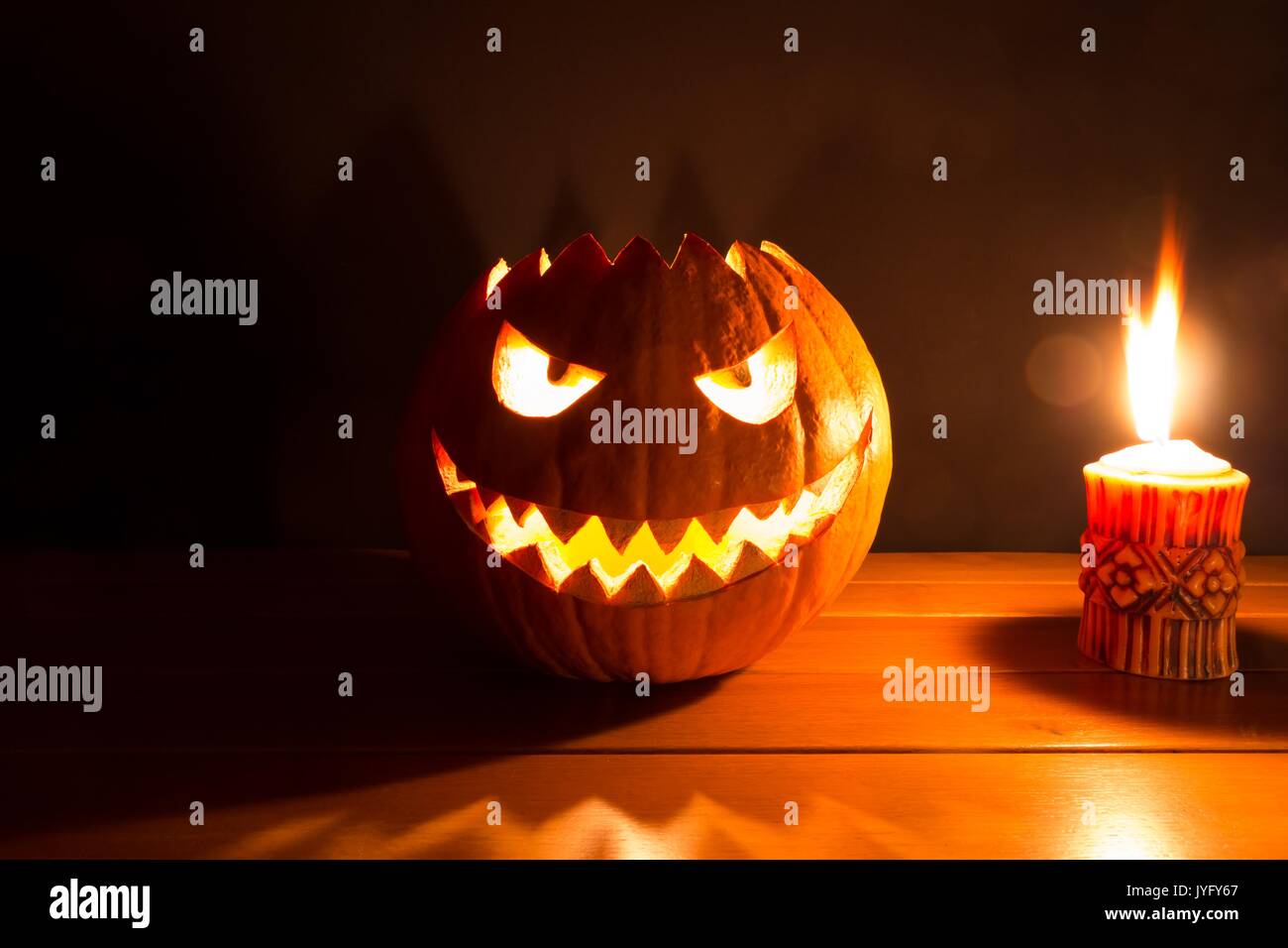 Spooky smiling halloween pumpkin with burning fire candle flame. The ...